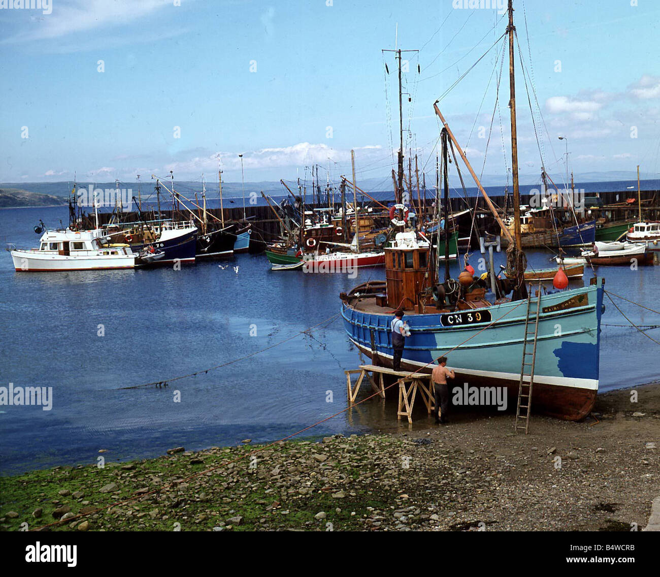 Harbour at Carradale Argyll Scotland Two fishermen are painting their ...