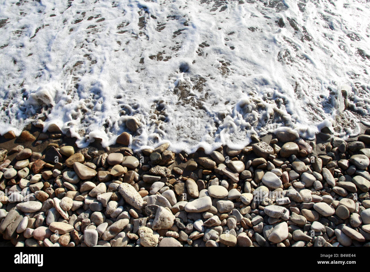 waves breaking onto rocks on sandy sea shore coast Stock Photo - Alamy