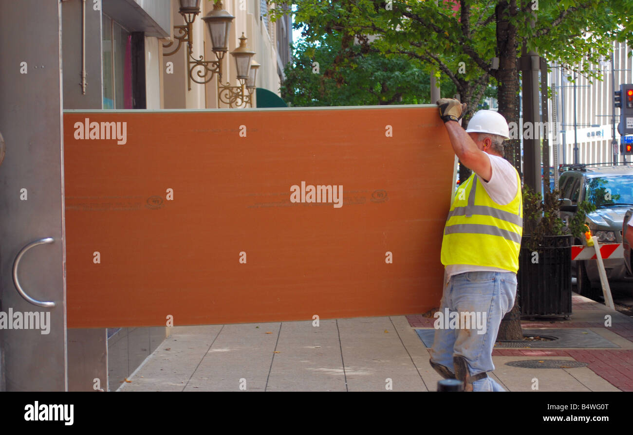Construction worker carrying a large piece of drywall Stock Photo - Alamy
