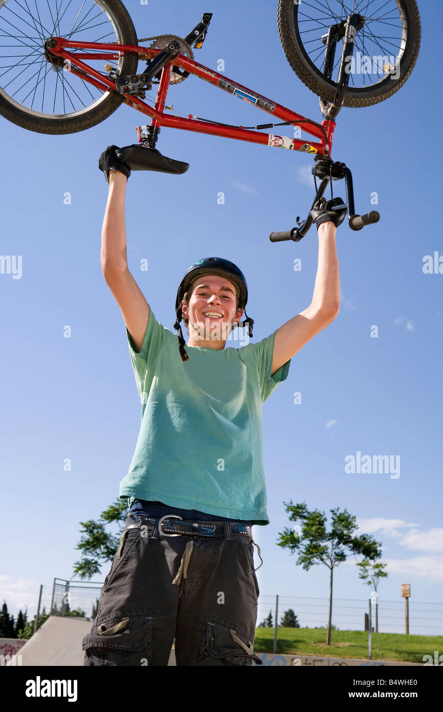 Teen boy carrying bike over his head Stock Photo - Alamy