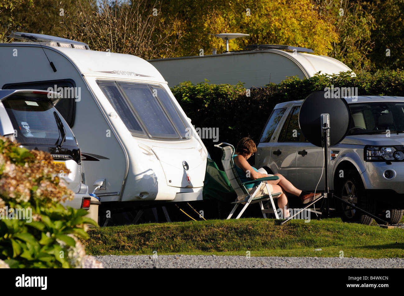 Caravan site in South Devon England UK Woman sitting and reading a book ...