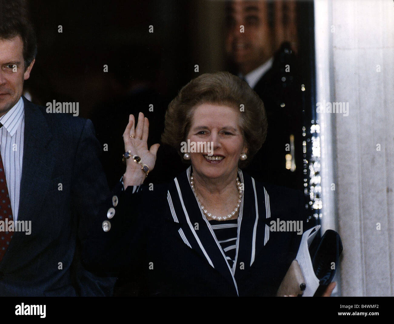 Prime Minister Margaret Thatcher waving as she walks out of the house ...