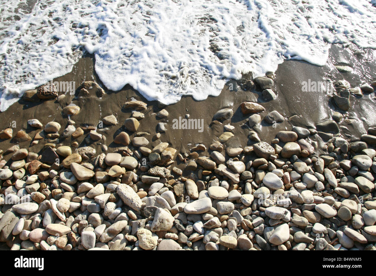 waves breaking onto rocks on sandy sea shore coast Stock Photo - Alamy