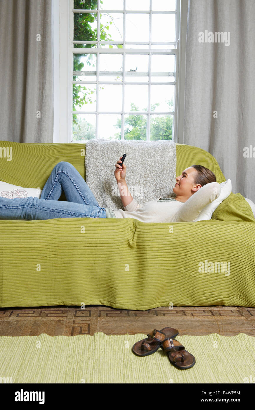 Young woman texting on couch Stock Photo - Alamy