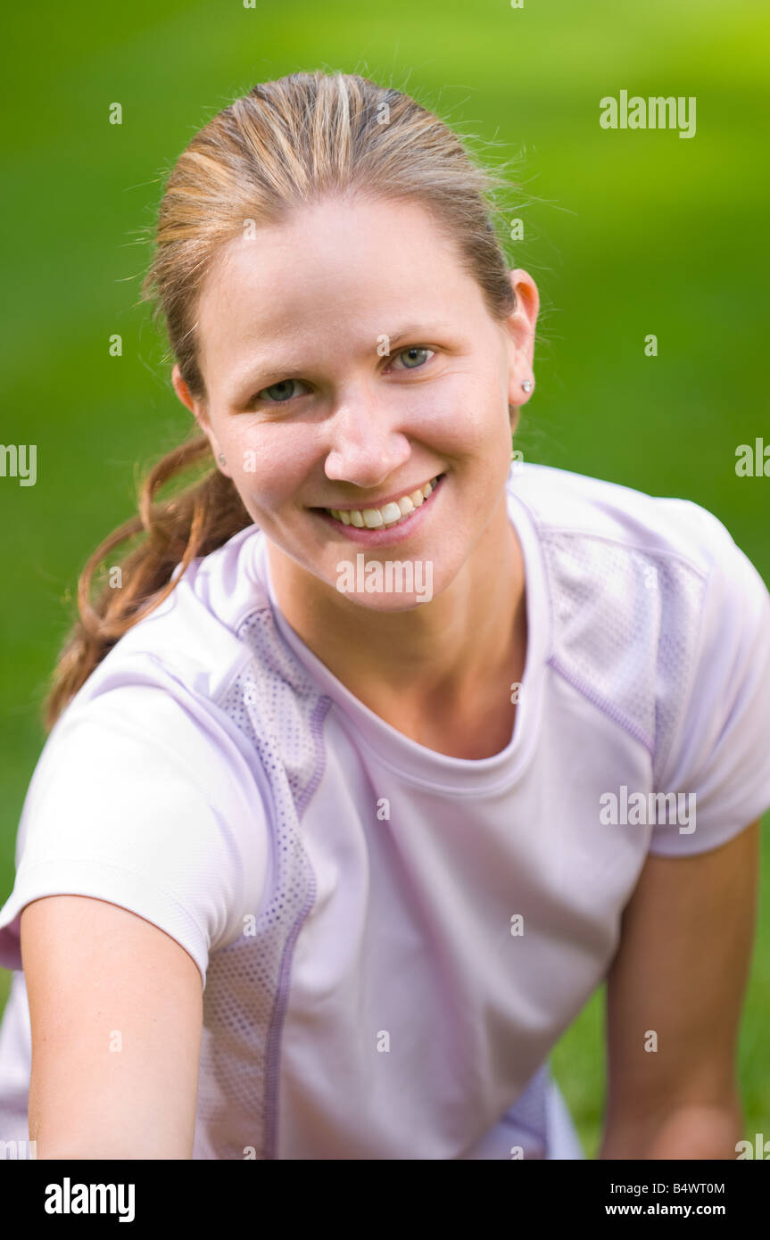 an attractive woman runner smiles for the camera while stretching ...