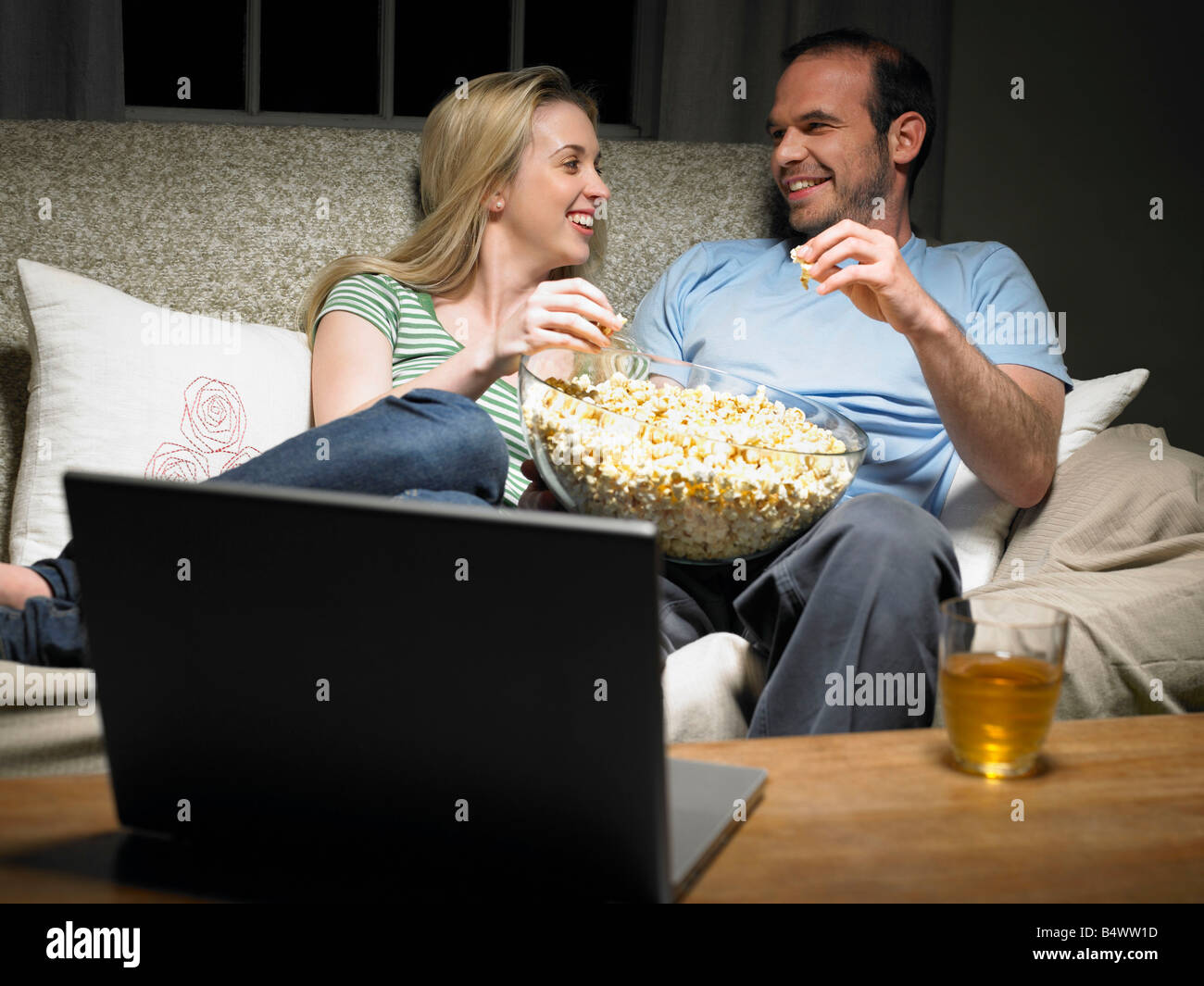 Young couple sharing popcorn on couch Stock Photo - Alamy