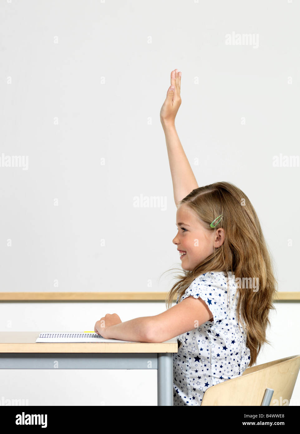 Girl raising hand in classroom Stock Photo - Alamy