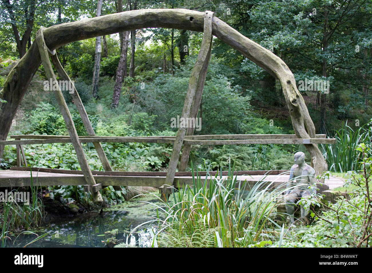 Green oak bridge over garden water feature with lifesize male bronze ...