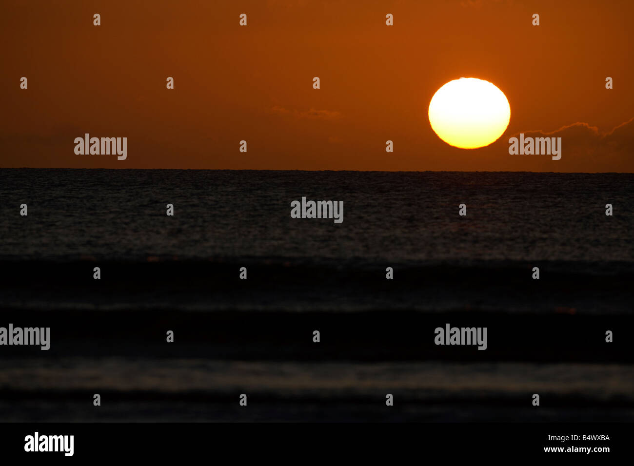the sun rising over the irish sea in early morning on newcastle beach ...