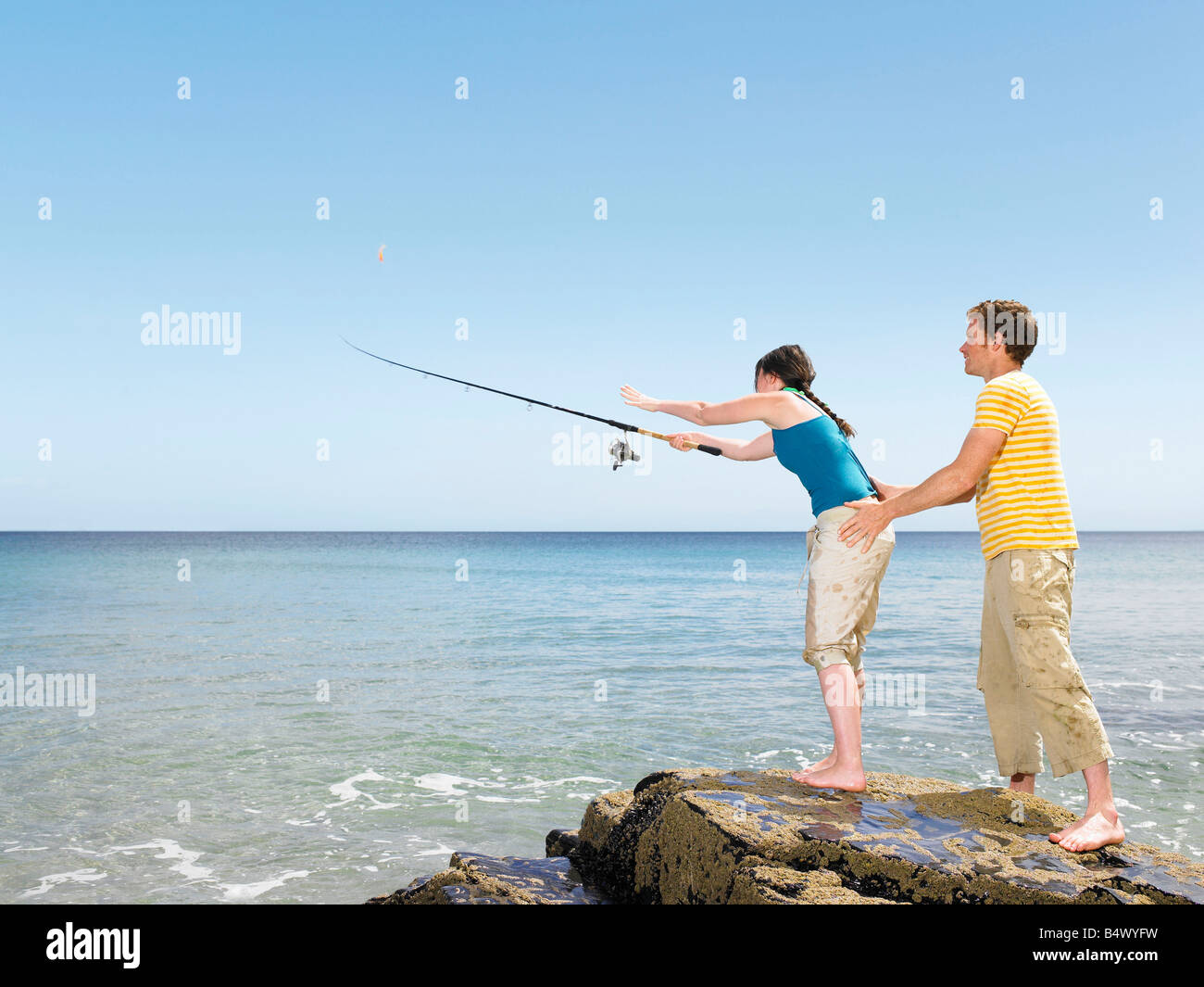 Couple fishing off rocks Stock Photo - Alamy