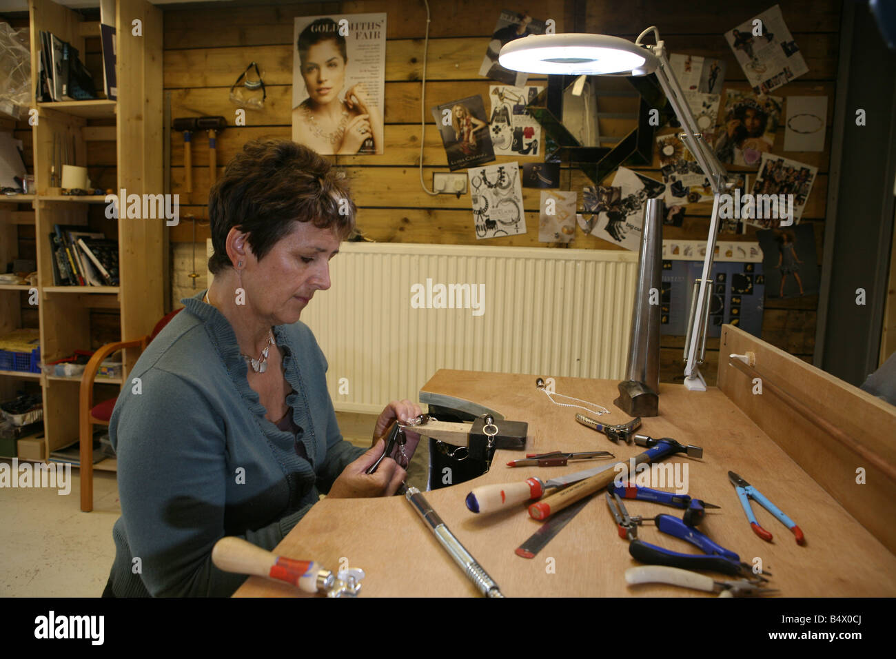 a female silversmith working on some jewelry rings and stuff in her ...