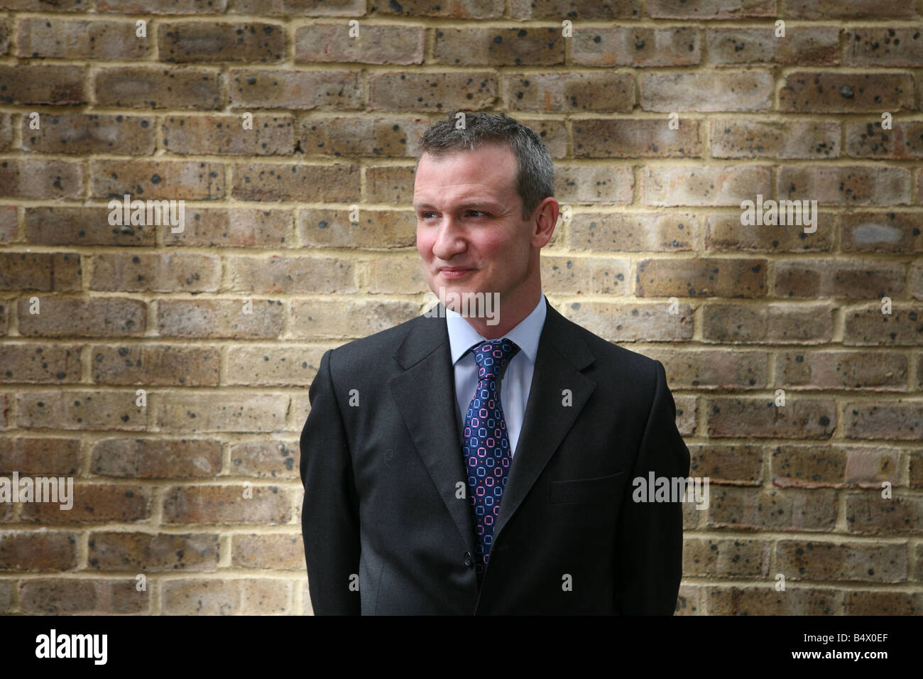 a portrait of a solicitor standing outside his office next to a brick ...