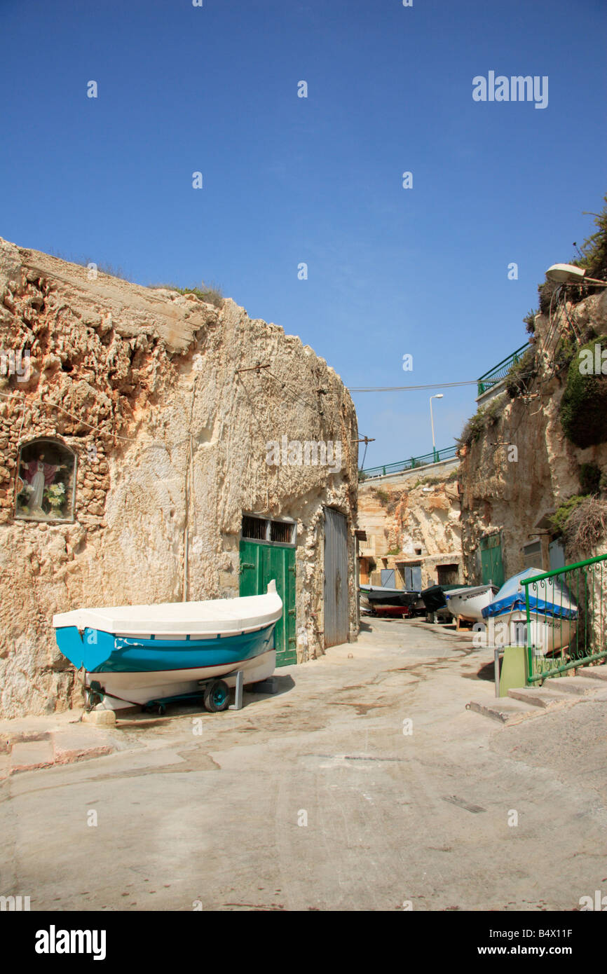 Boathouses cut into the cliff and boats at Ghar Lapsi, Malta Stock ...