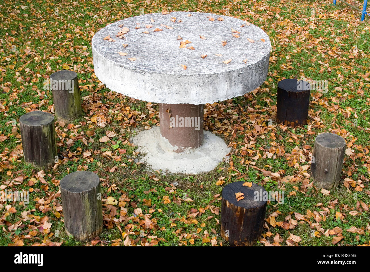 Concrete round table with wooden chairs around it Stock Photo - Alamy
