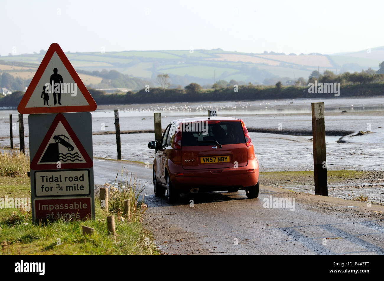 Car driving on tidal road alongside River Avon at Aveton Gifford Devon ...