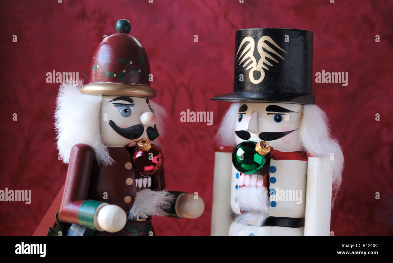 two nutcrackers with glass ornaments in their mouths on a red ...