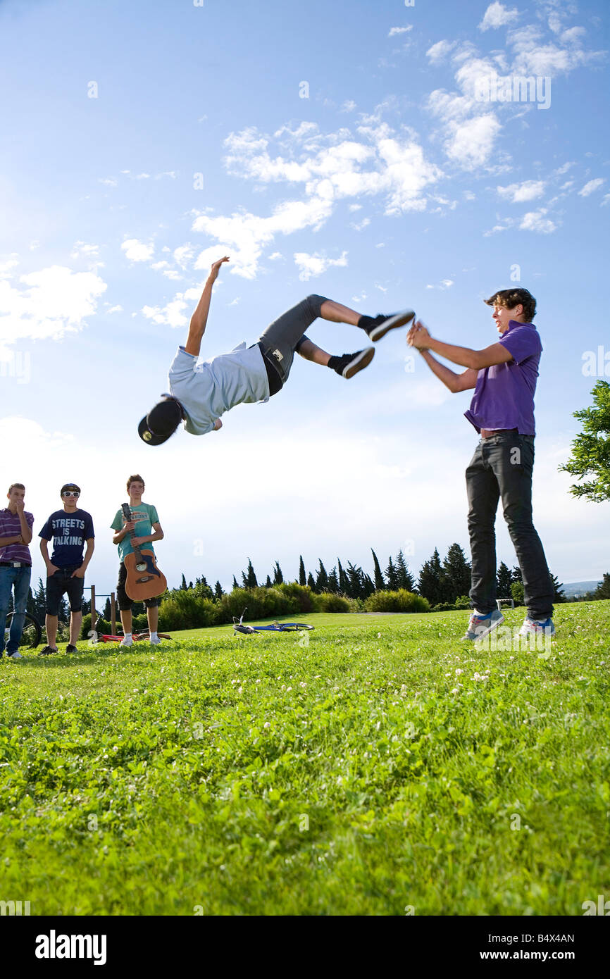 Teen boys help friend to do a flip Stock Photo - Alamy