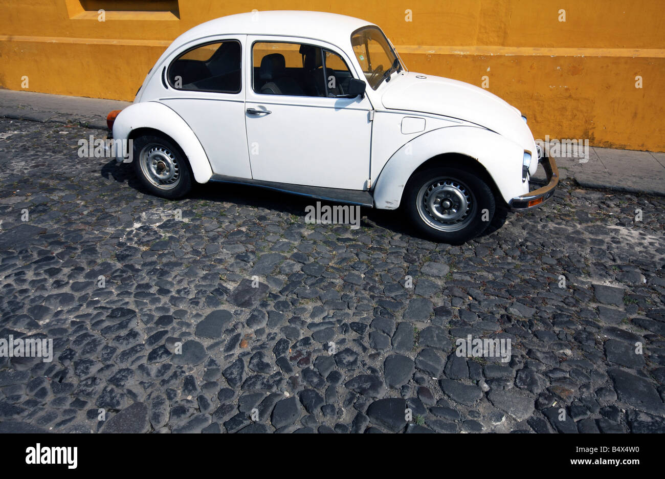 A white Volkswagen Beetle parked on a cobbled street in the old ...