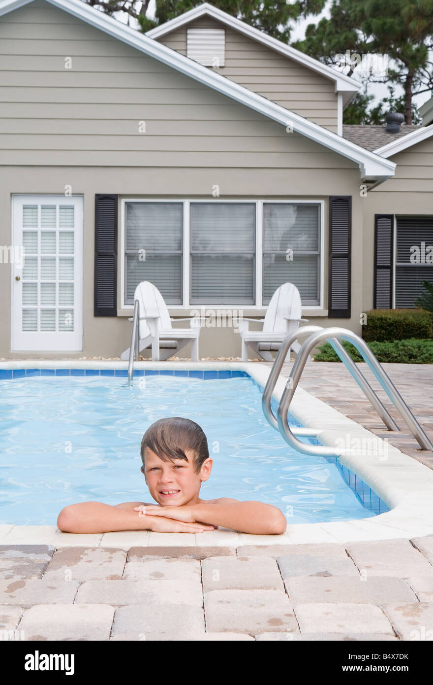 Boy leaning on edge of swimming pool Stock Photo - Alamy
