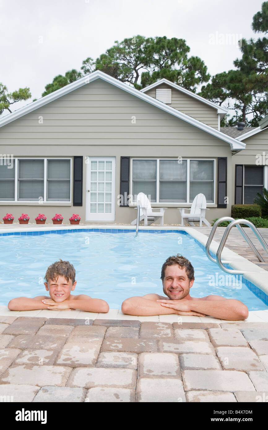 Father and son leaning on edge of swimming pool Stock Photo - Alamy