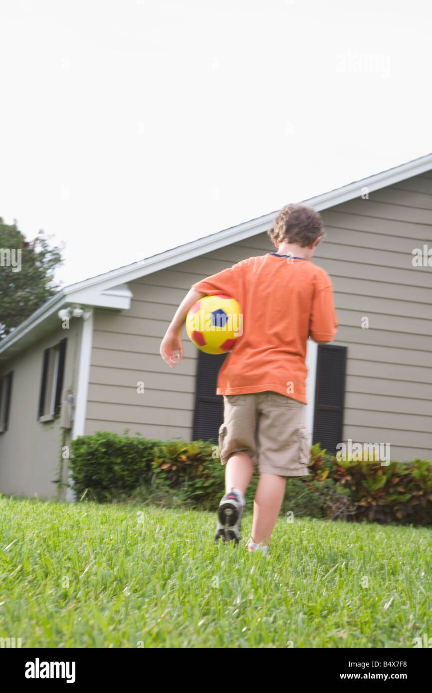 Boy carrying soccer ball in backyard Stock Photo - Alamy