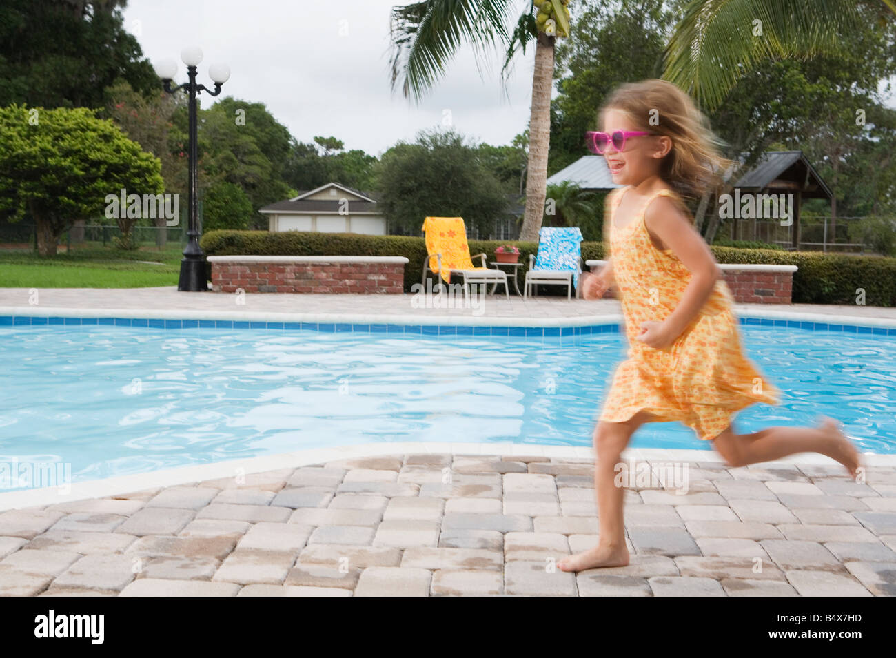 Girl running beside swimming pool Stock Photo - Alamy