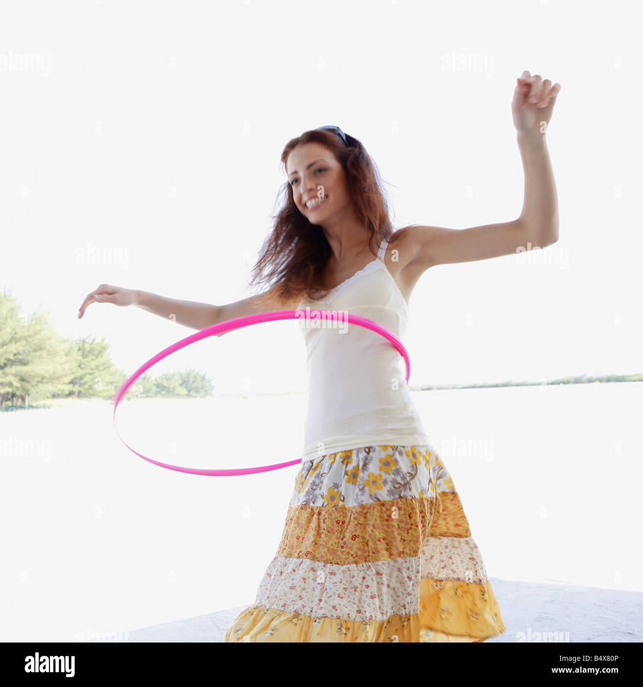 Young woman hula hooping on beach Stock Photo - Alamy