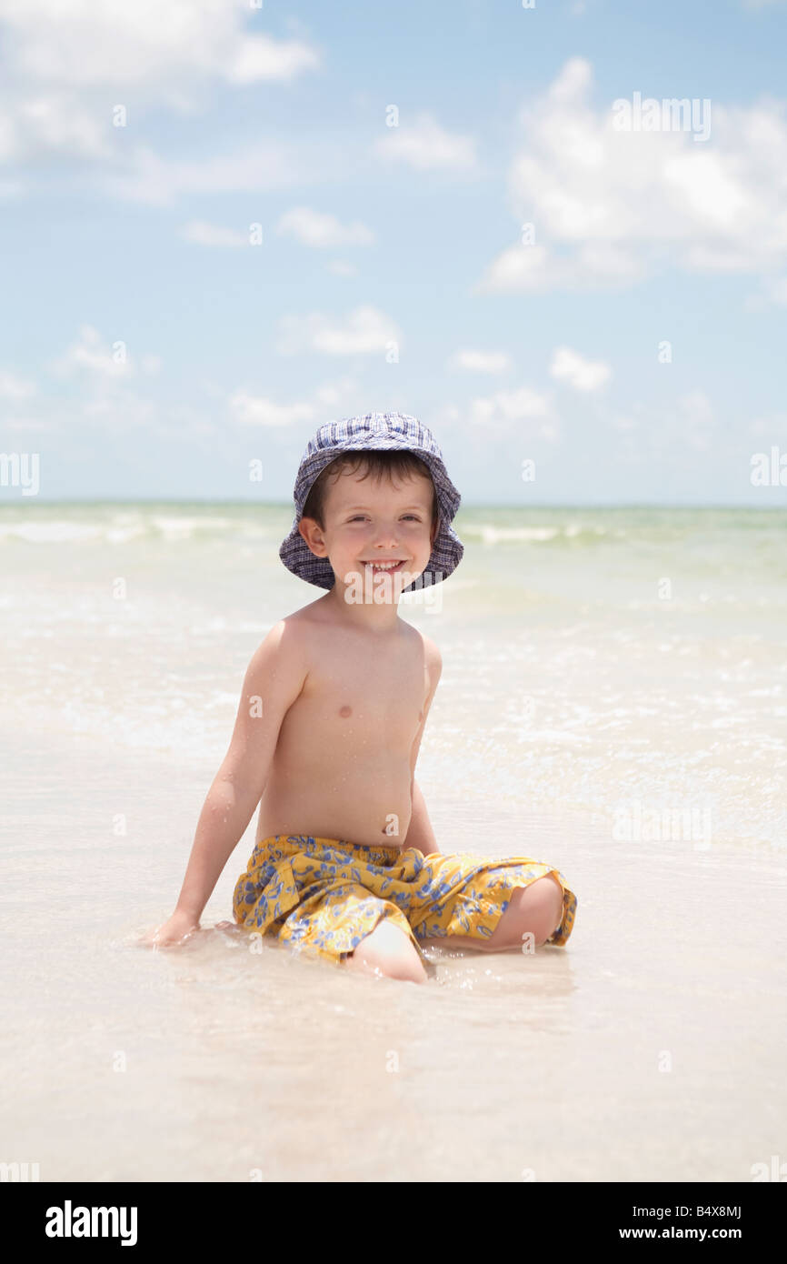 Boy sitting in shallow ocean Stock Photo - Alamy