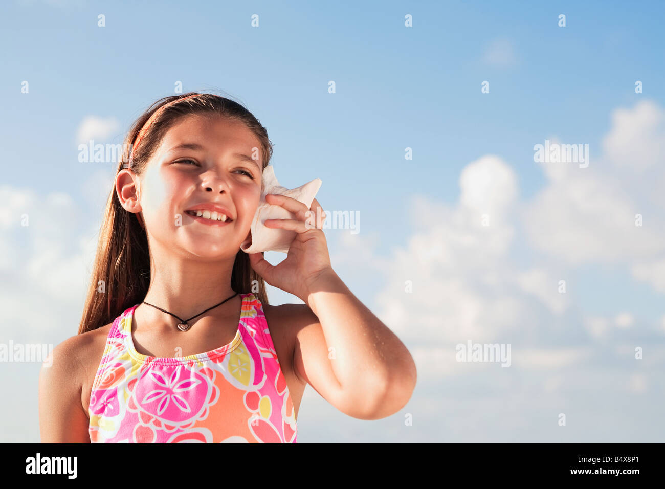 Girl holding conch shell to ear Stock Photo - Alamy