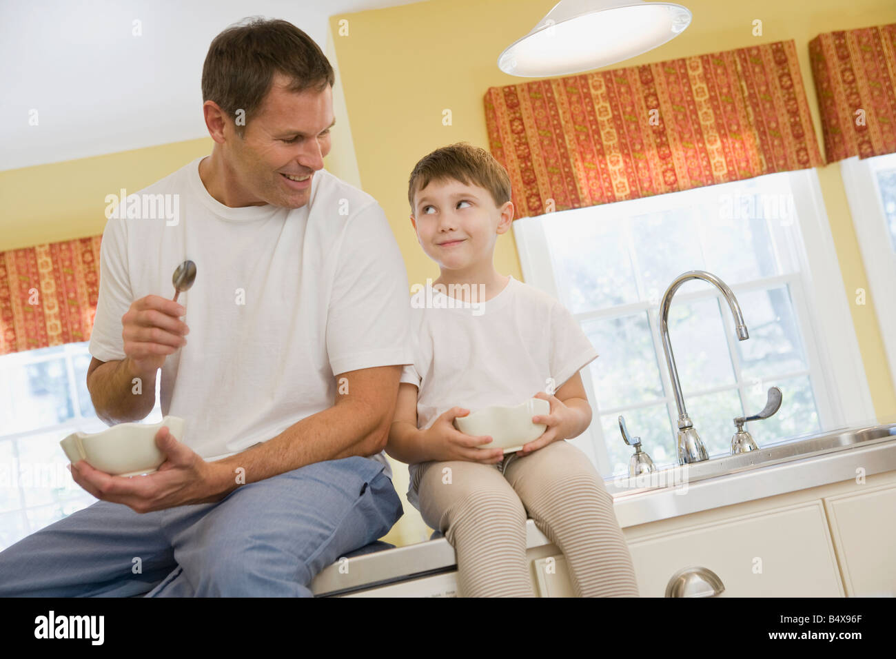 Father and son eating breakfast on kitchen counter Stock Photo - Alamy