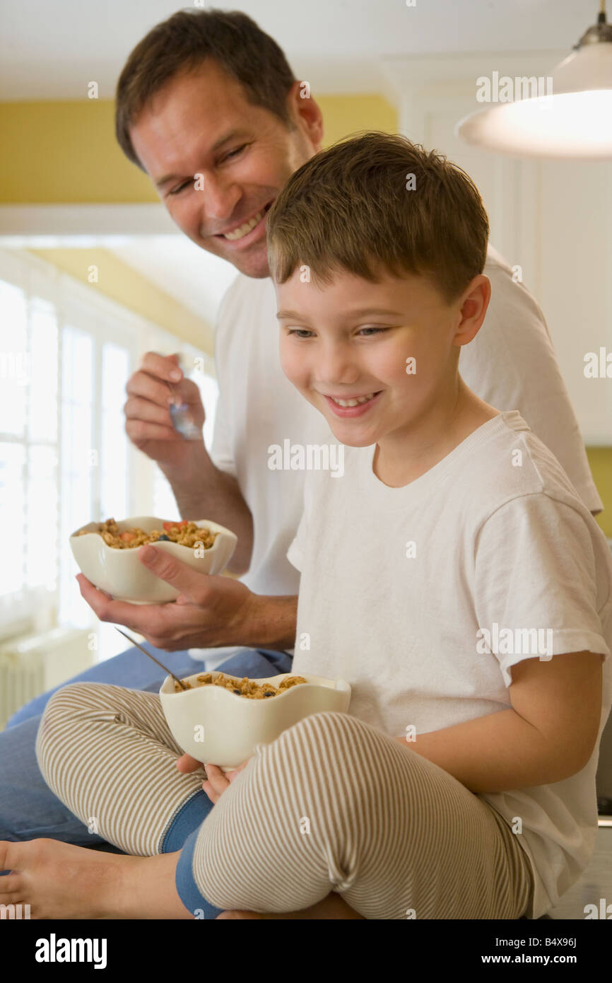 Father and son eating breakfast on kitchen counter Stock Photo - Alamy