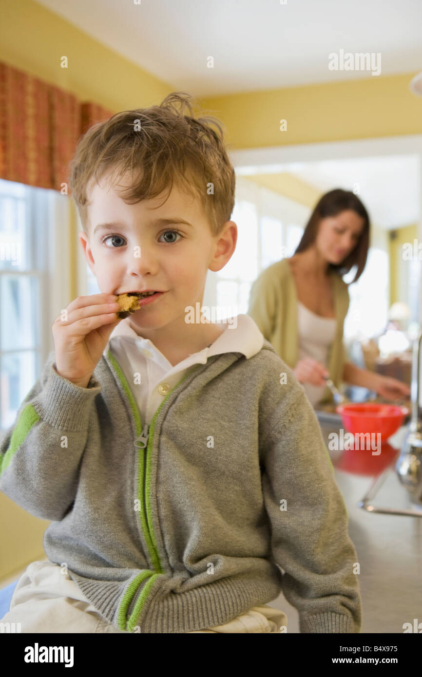 Boy eating cookie on kitchen counter Stock Photo - Alamy