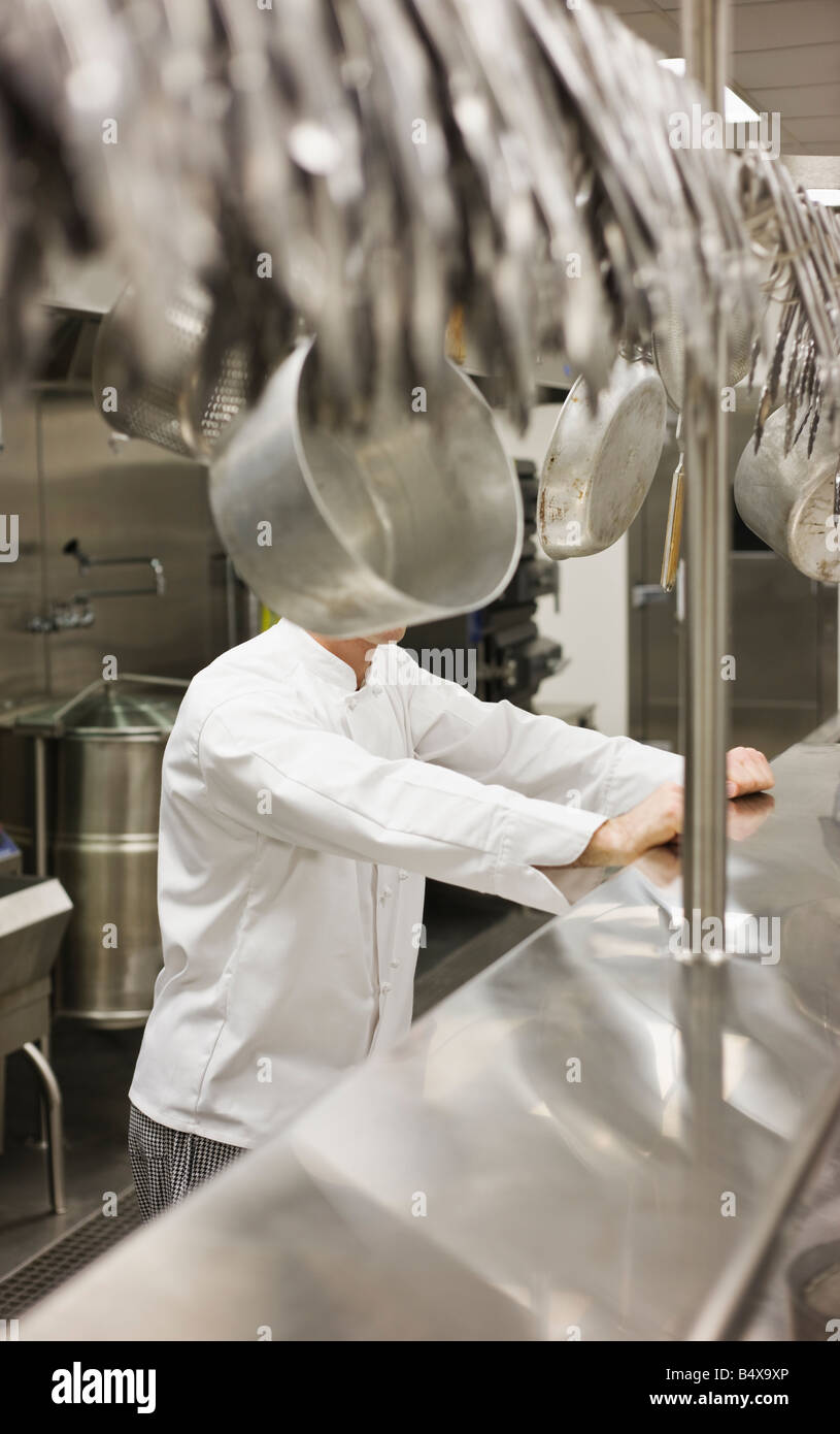 Chef leaning on shelf in commercial kitchen Stock Photo - Alamy