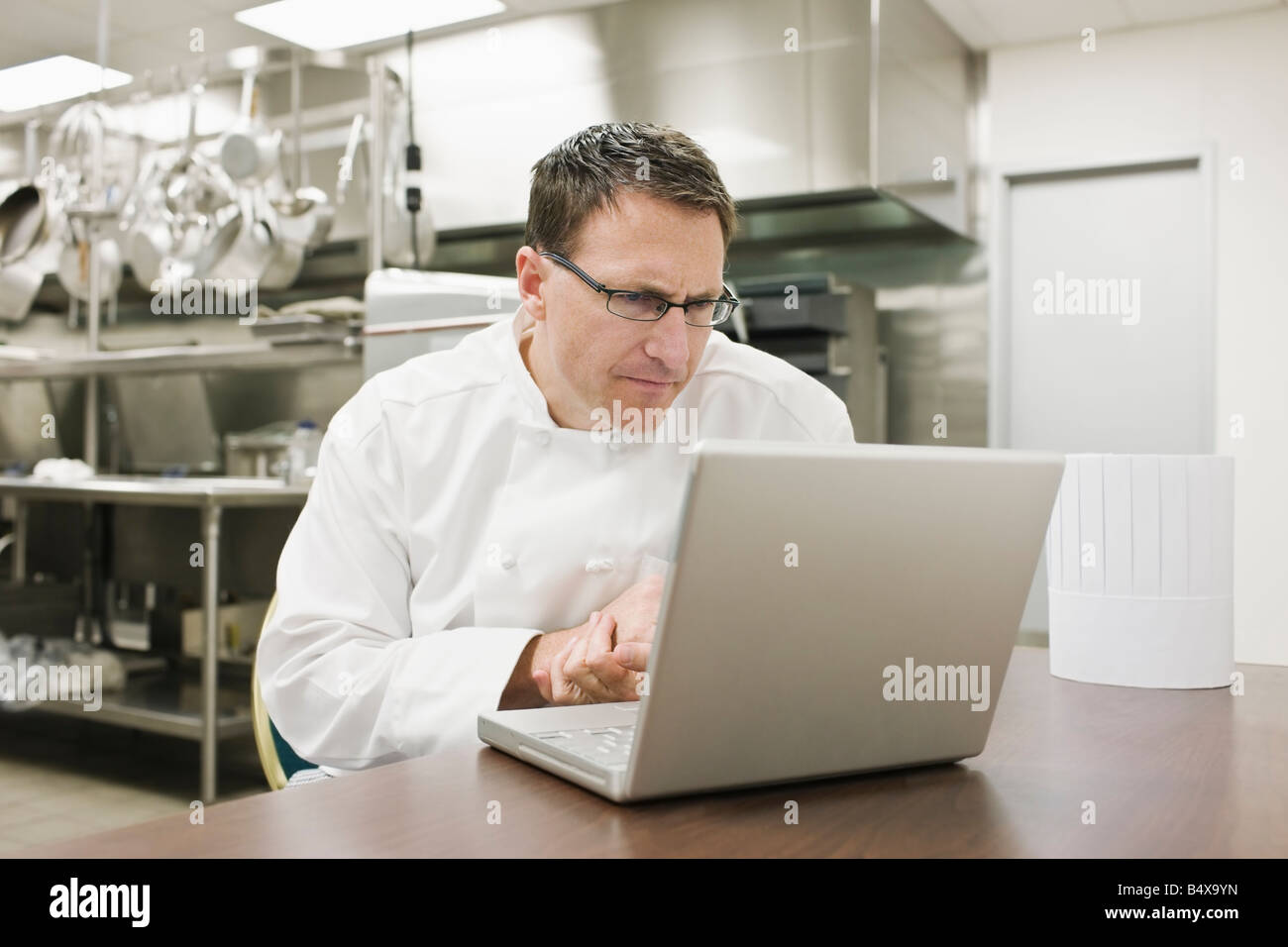 Frustrated chef looking at laptop in kitchen Stock Photo - Alamy