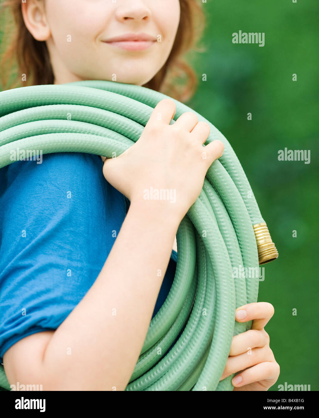 Teenage girl carrying garden hose Stock Photo - Alamy