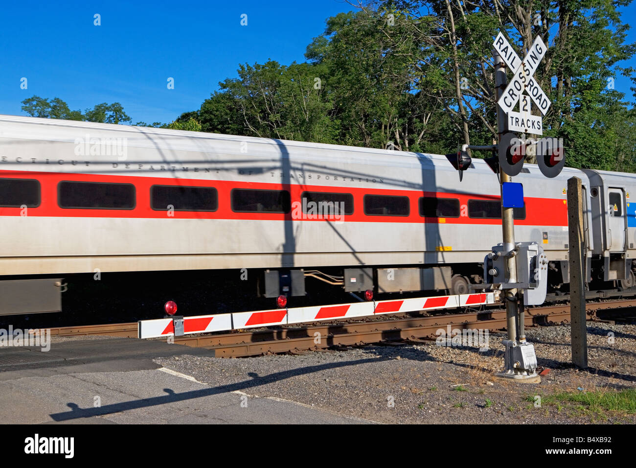 Commuter train and road crossing Stock Photo - Alamy