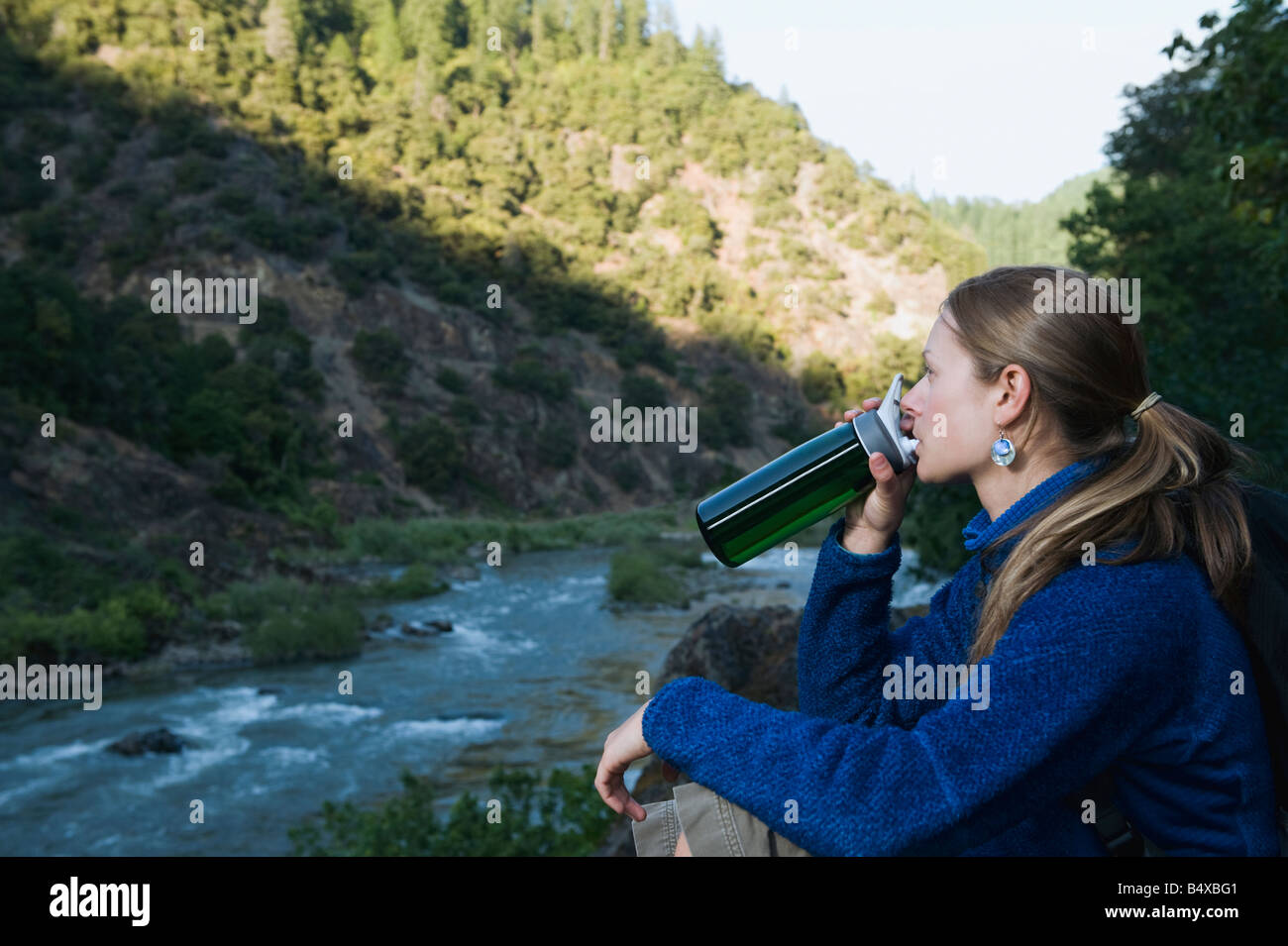 Young woman drinking water on river overlook Stock Photo - Alamy