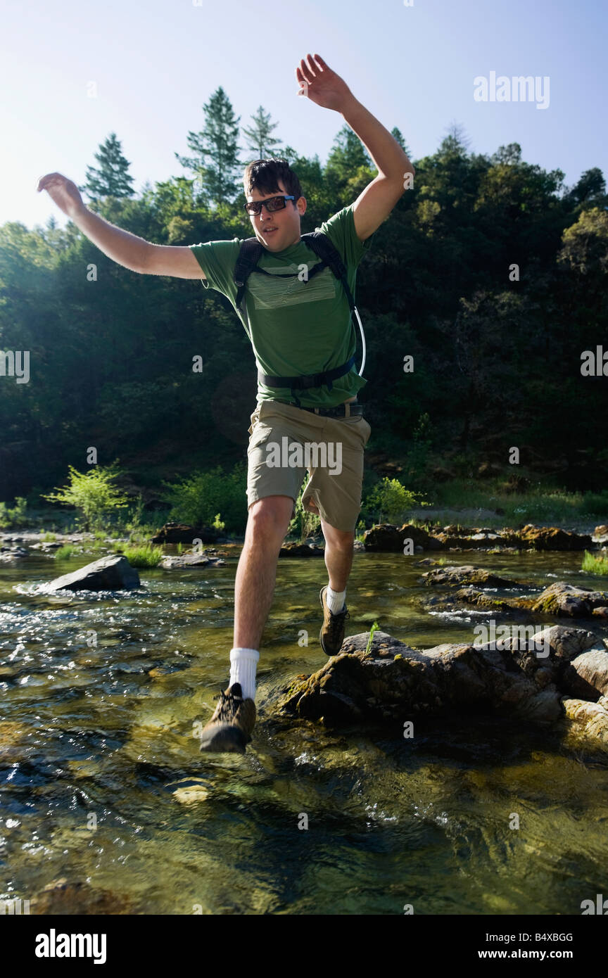 Man jumping across river on rocks Stock Photo - Alamy