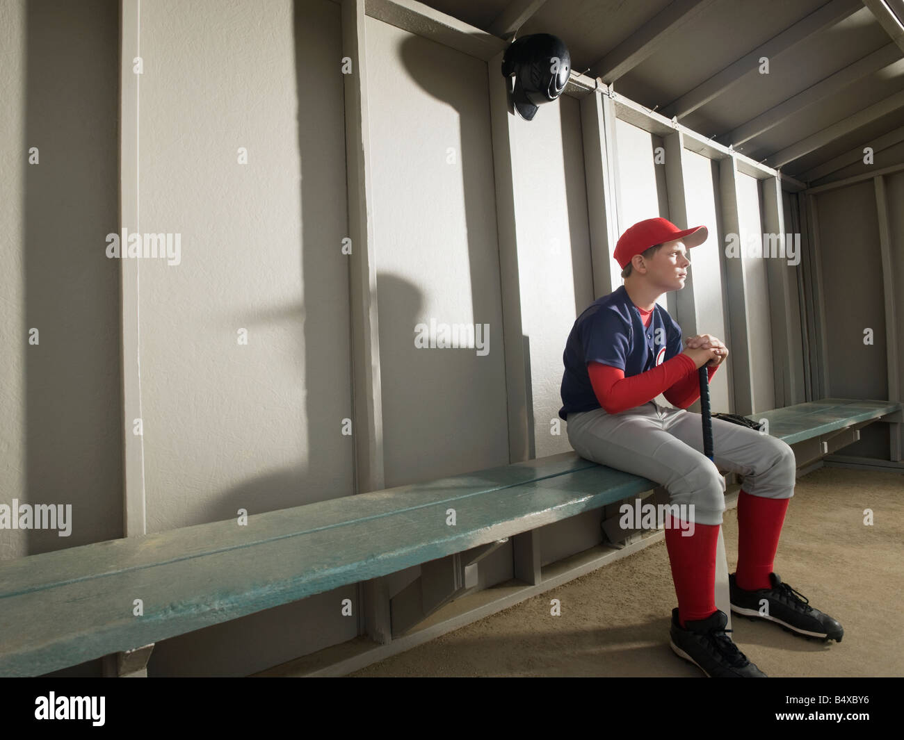 Serious baseball player sitting in dugout Stock Photo - Alamy