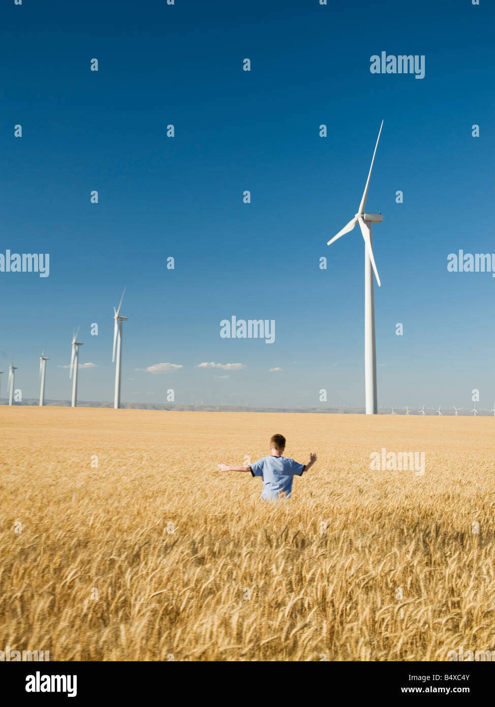 Boy running through field on wind farm Stock Photo - Alamy