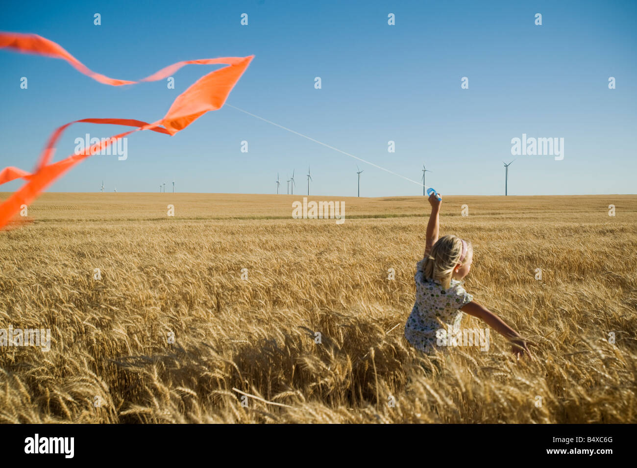 Girl running with kite on wind farm Stock Photo - Alamy