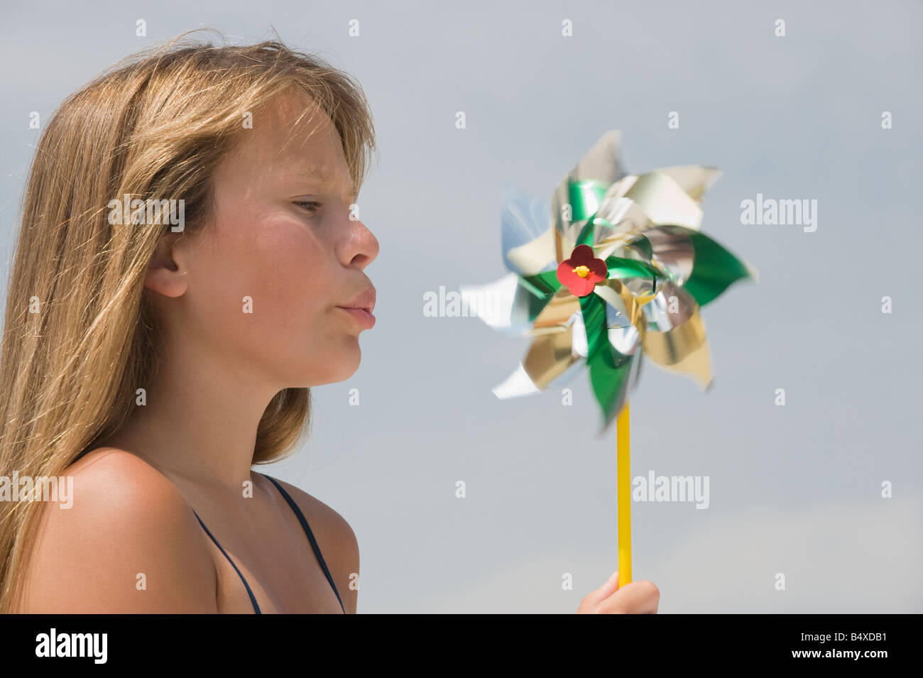 Girl blowing on pinwheel Stock Photo - Alamy
