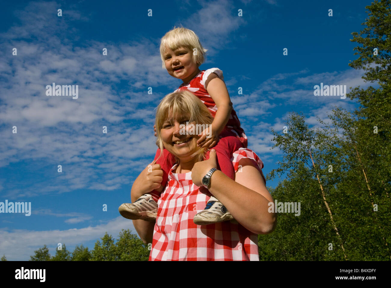 Young happy girl sitting on mothers shoulder Stock Photo - Alamy