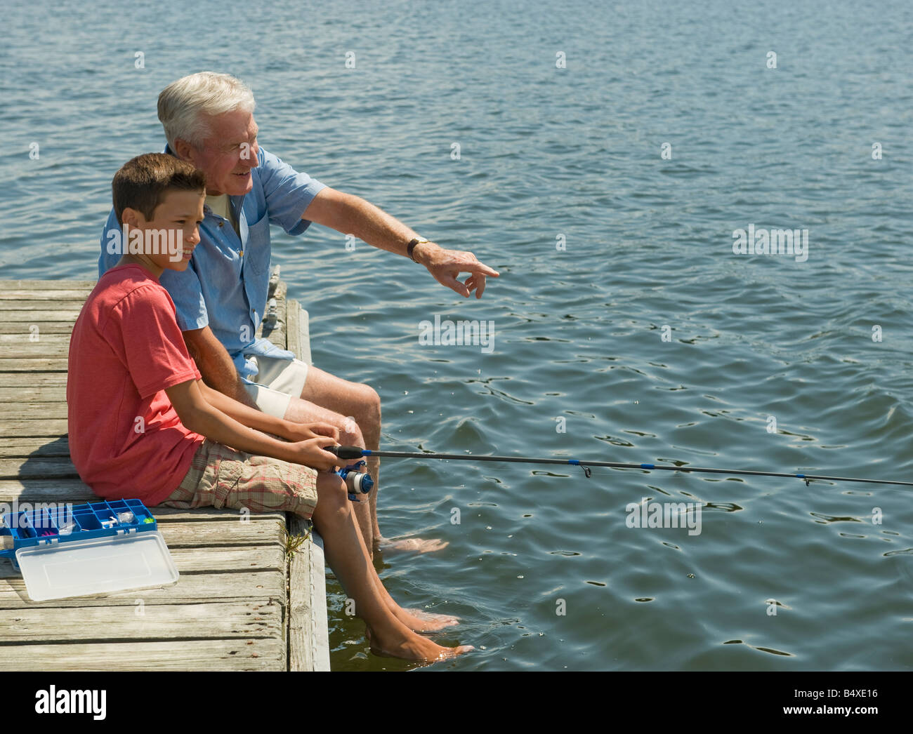 Grandfather and grandson fishing off dock Stock Photo - Alamy