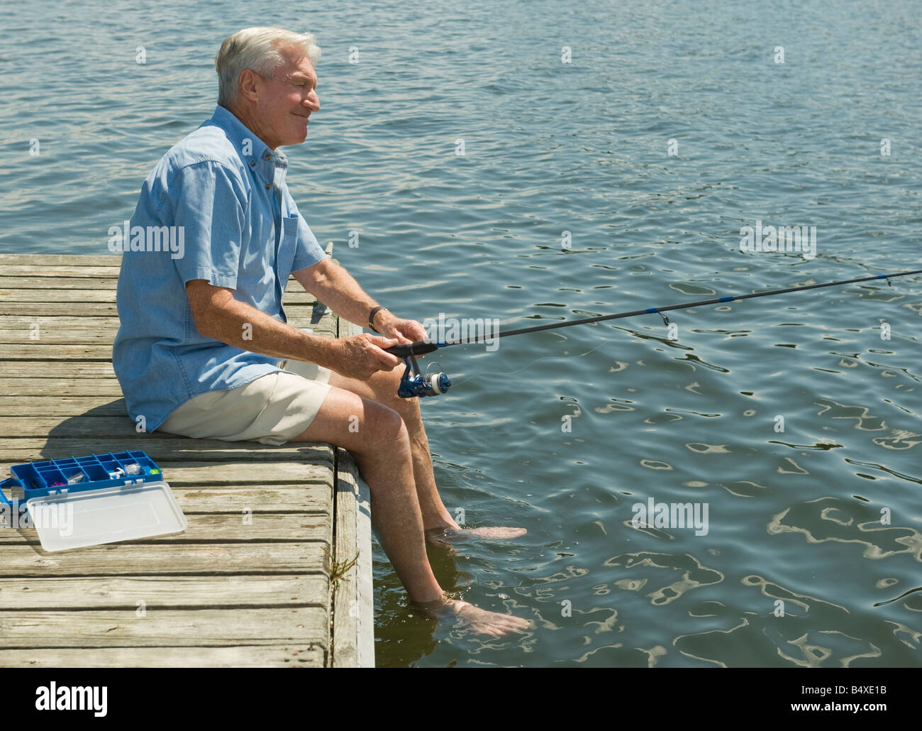 Senior man fishing off dock Stock Photo - Alamy