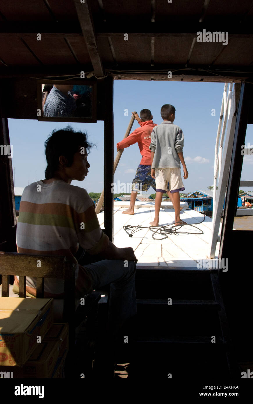 Two young boys help the captain to navigate a pleasure craft Lake Tonle ...