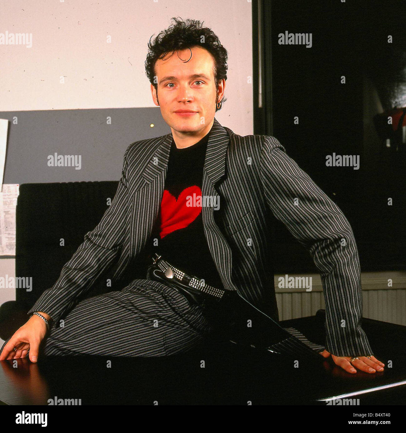 Adam Ant pop singer sitting on desk January 1990 Striped suit black ...
