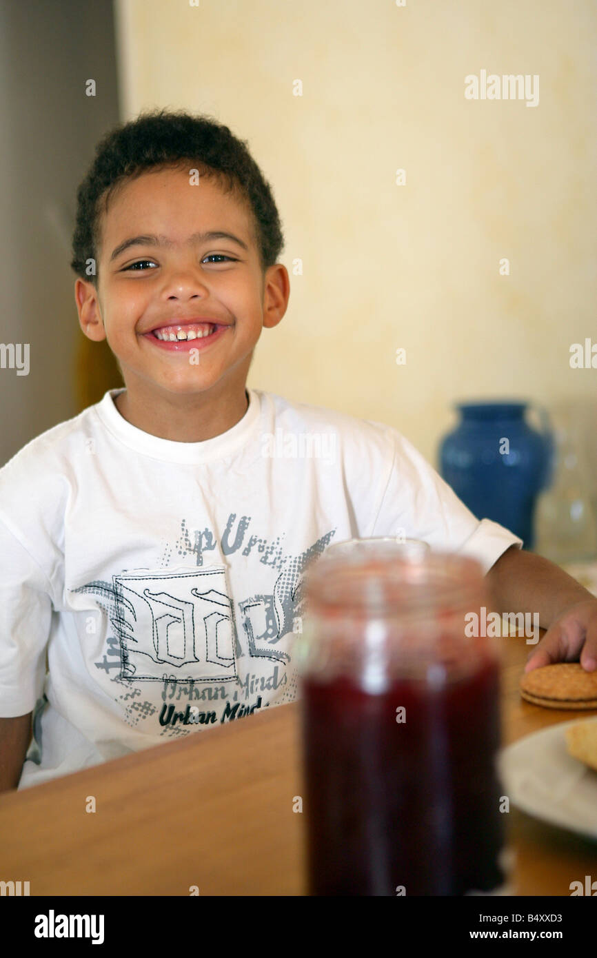 Cheerful boy sitting by table with jam in the foreground Stock Photo ...