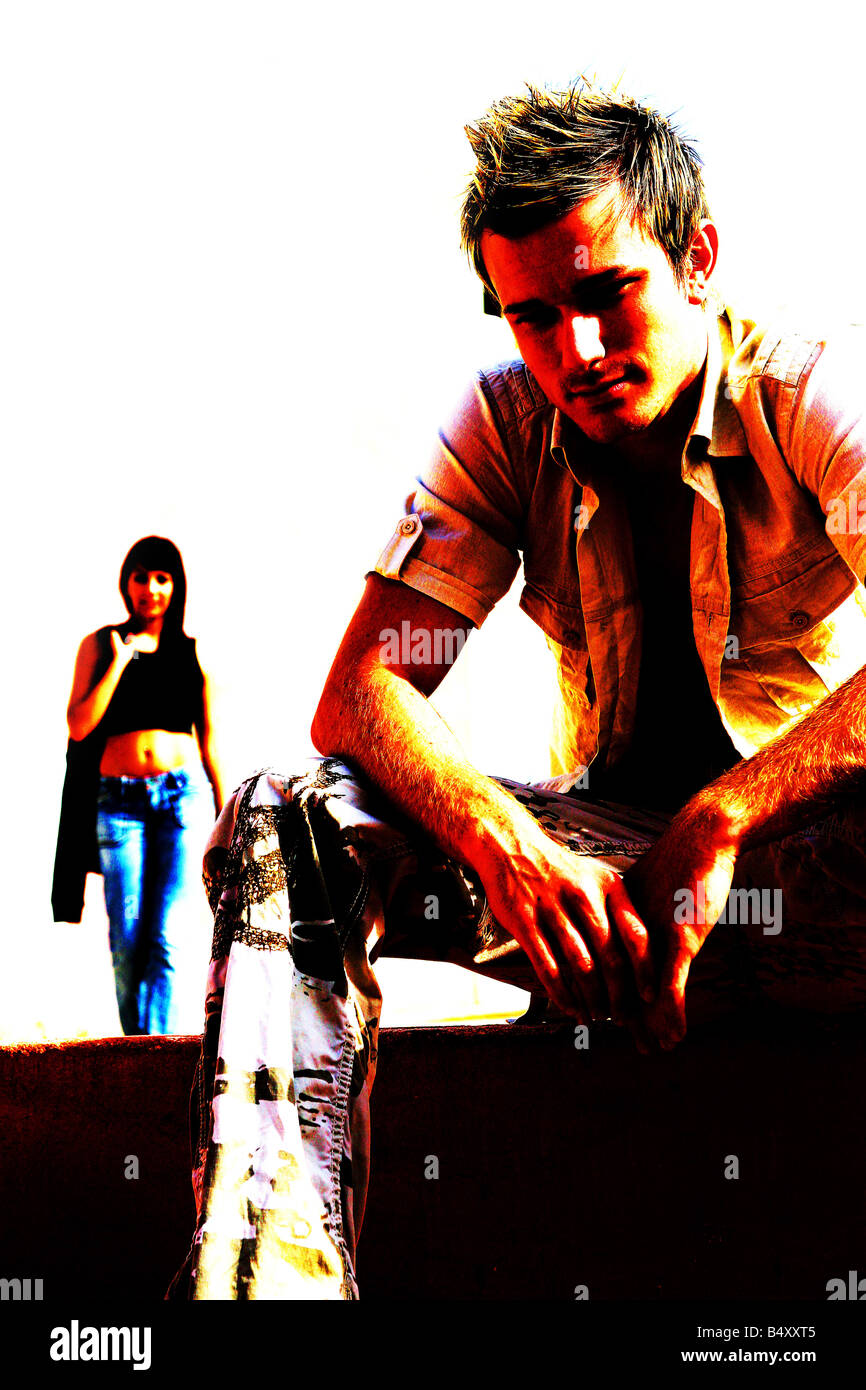 Young man sitting while young woman standing in background Stock Photo ...