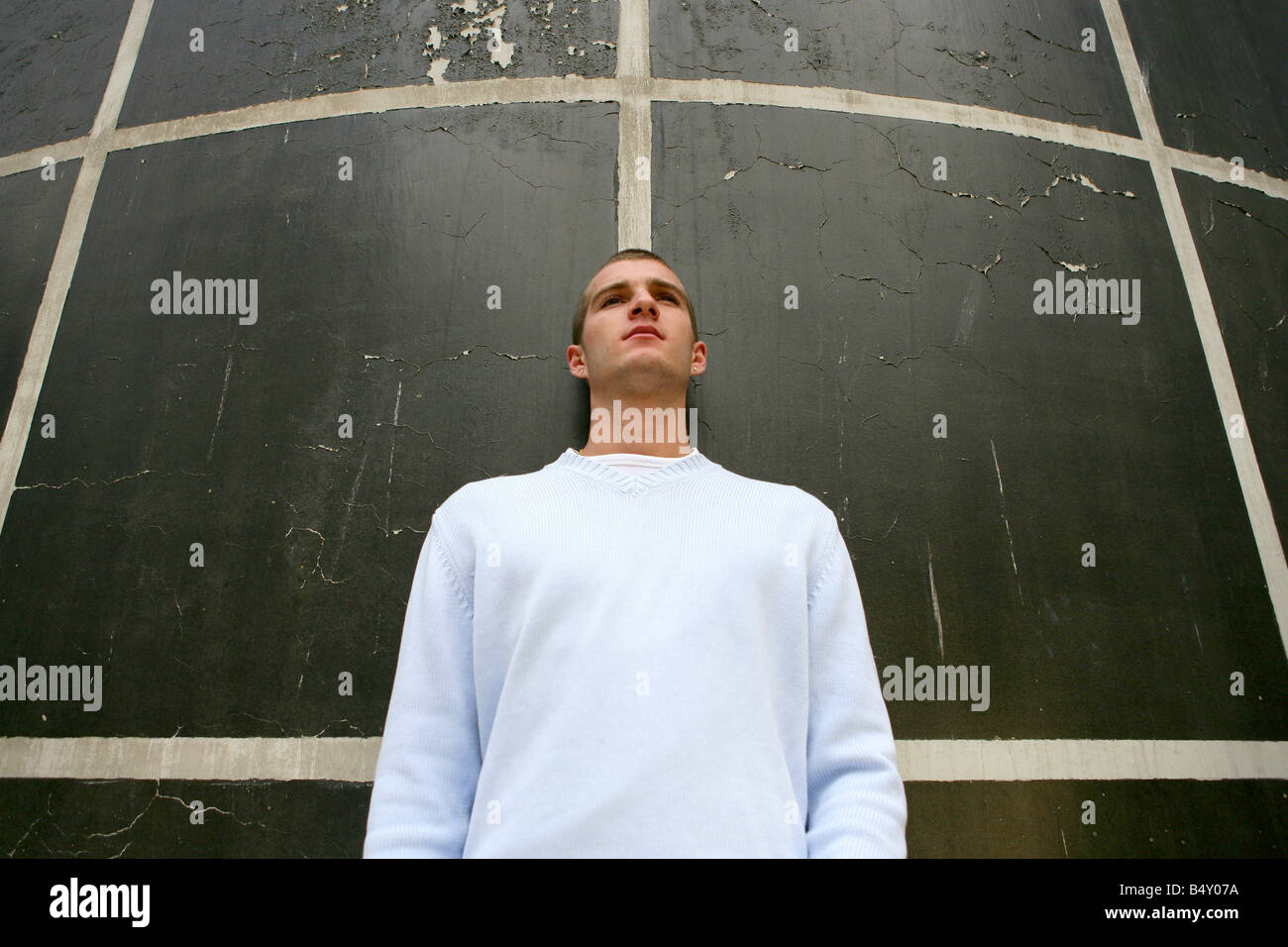 Young man standing by wall Stock Photo - Alamy